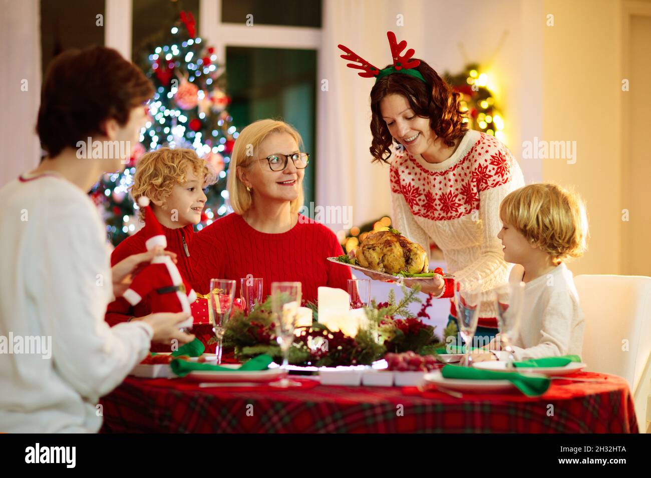 Family with children eating Christmas dinner at fireplace and decorated ...