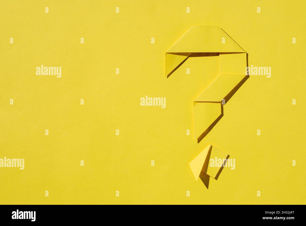 Monochromatic yellow background of a folded paper origami question mark ...