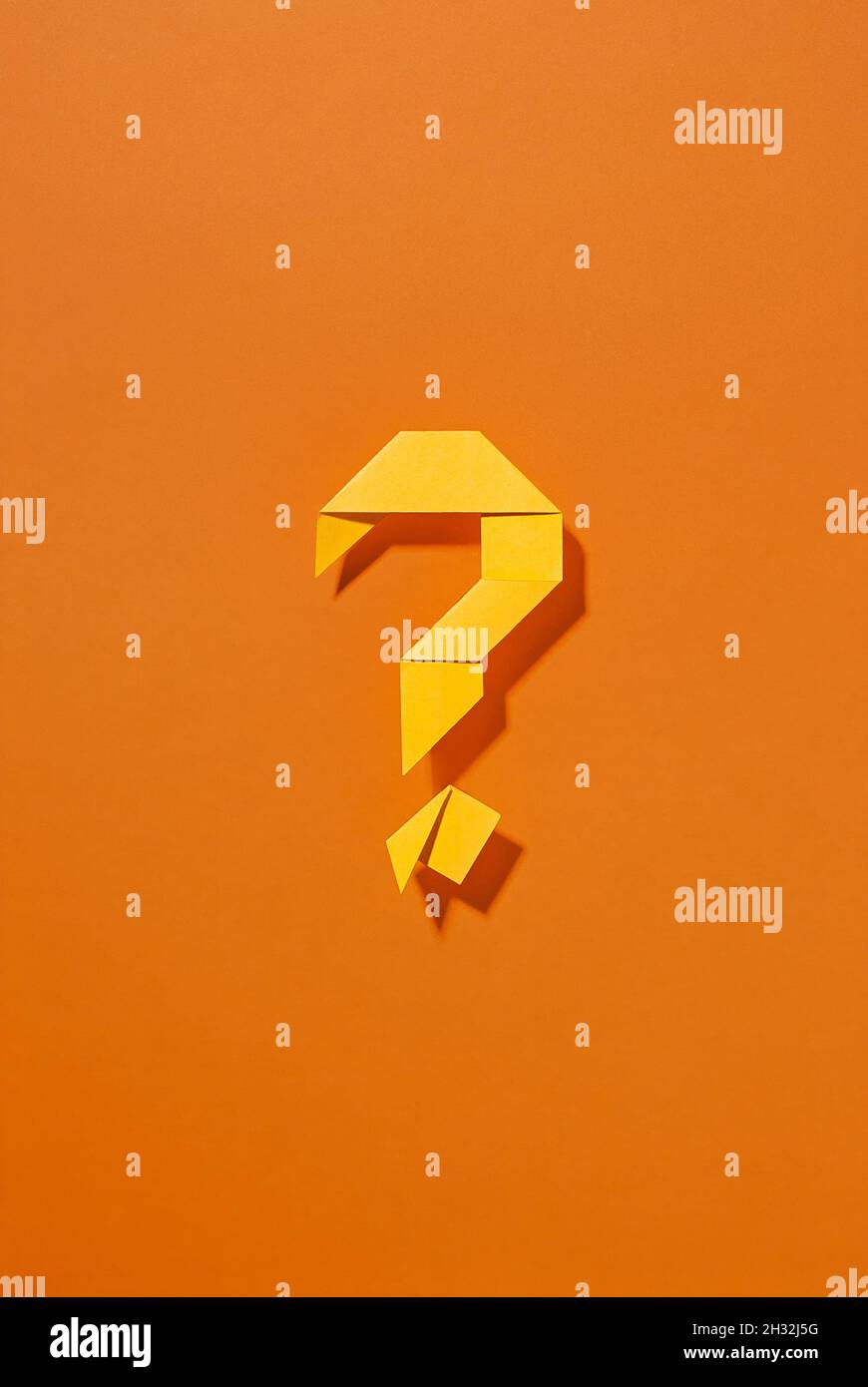 Colorful yellow origami question mark with shadow centered on orange ...