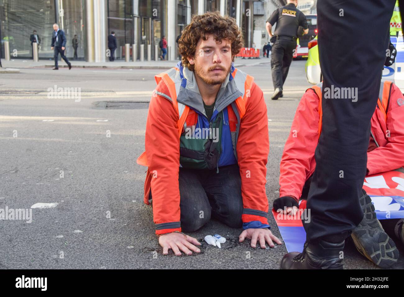 London, UK. 25th October 2021. A protester with his hands superglued to ...