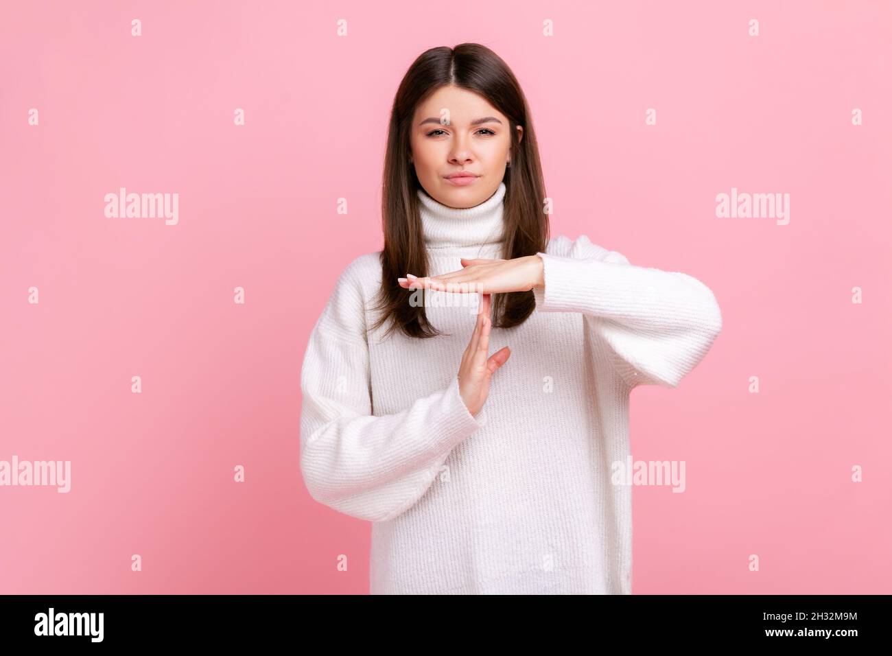 Serious female with dark hair showing time out gesture, looking with ...
