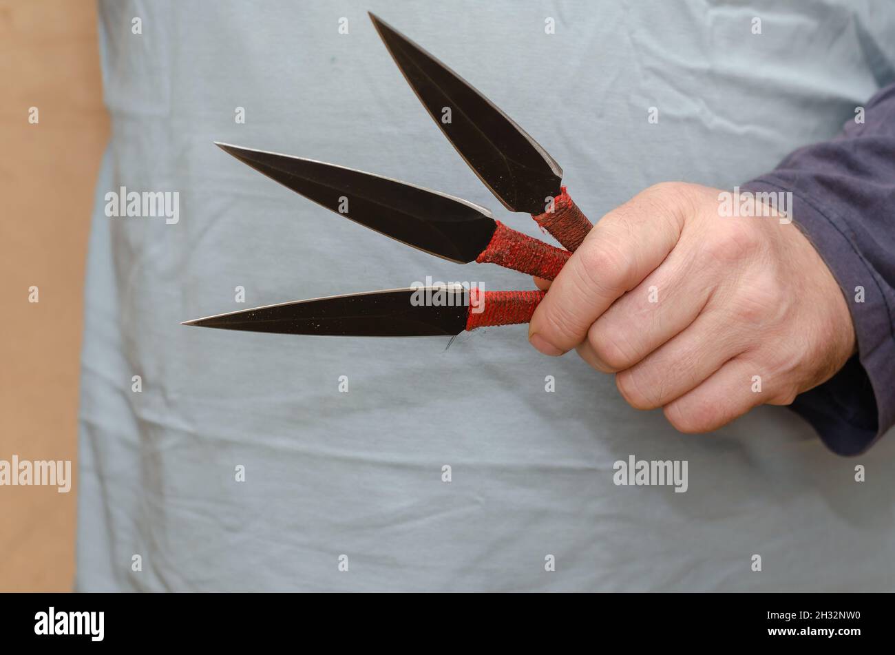 A hand with three knives. Adult male holding throwing knives Stock ...