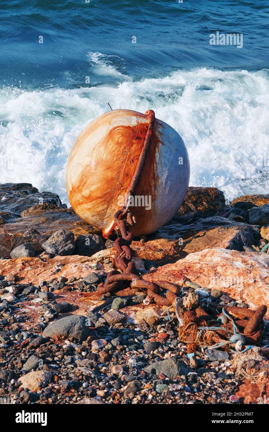 Big rusty white round buoy and chain on the shore with sea background ...