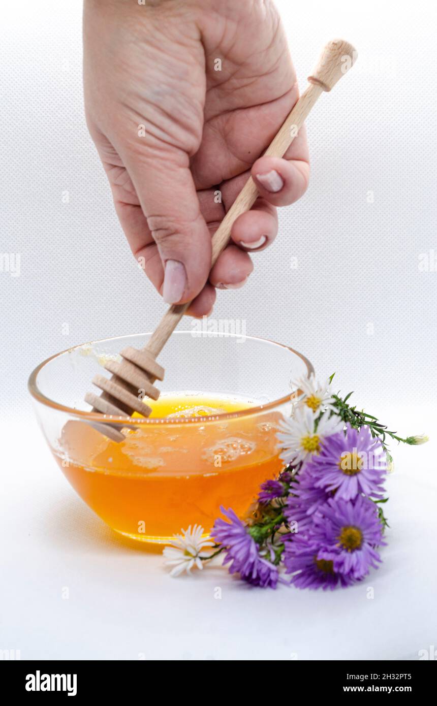a woman's hand is stirring the honey with a honey dipper Stock Photo ...