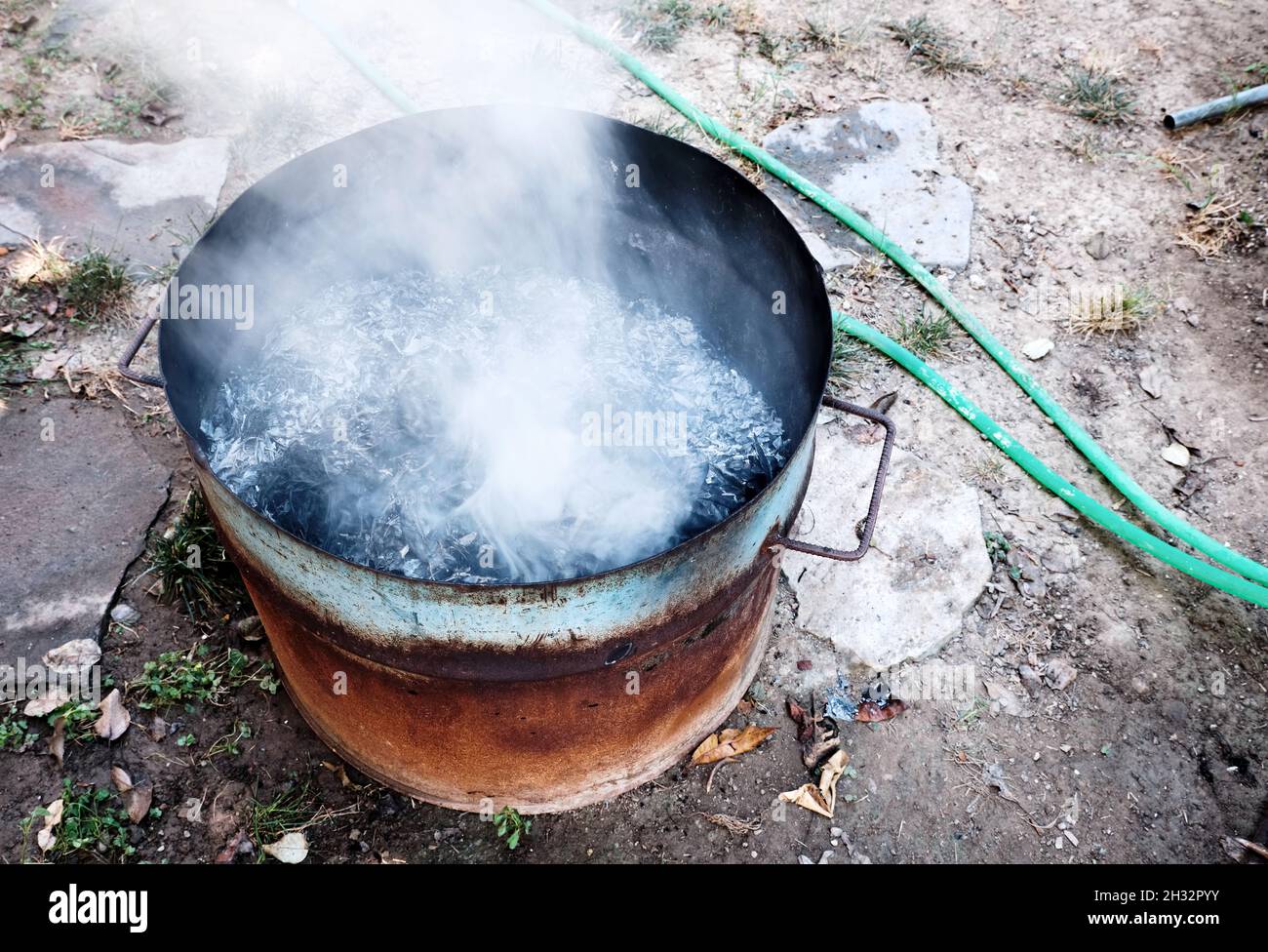 Burning leaf ashes and smoke in a metal barrel. Sanitary treatment of ...