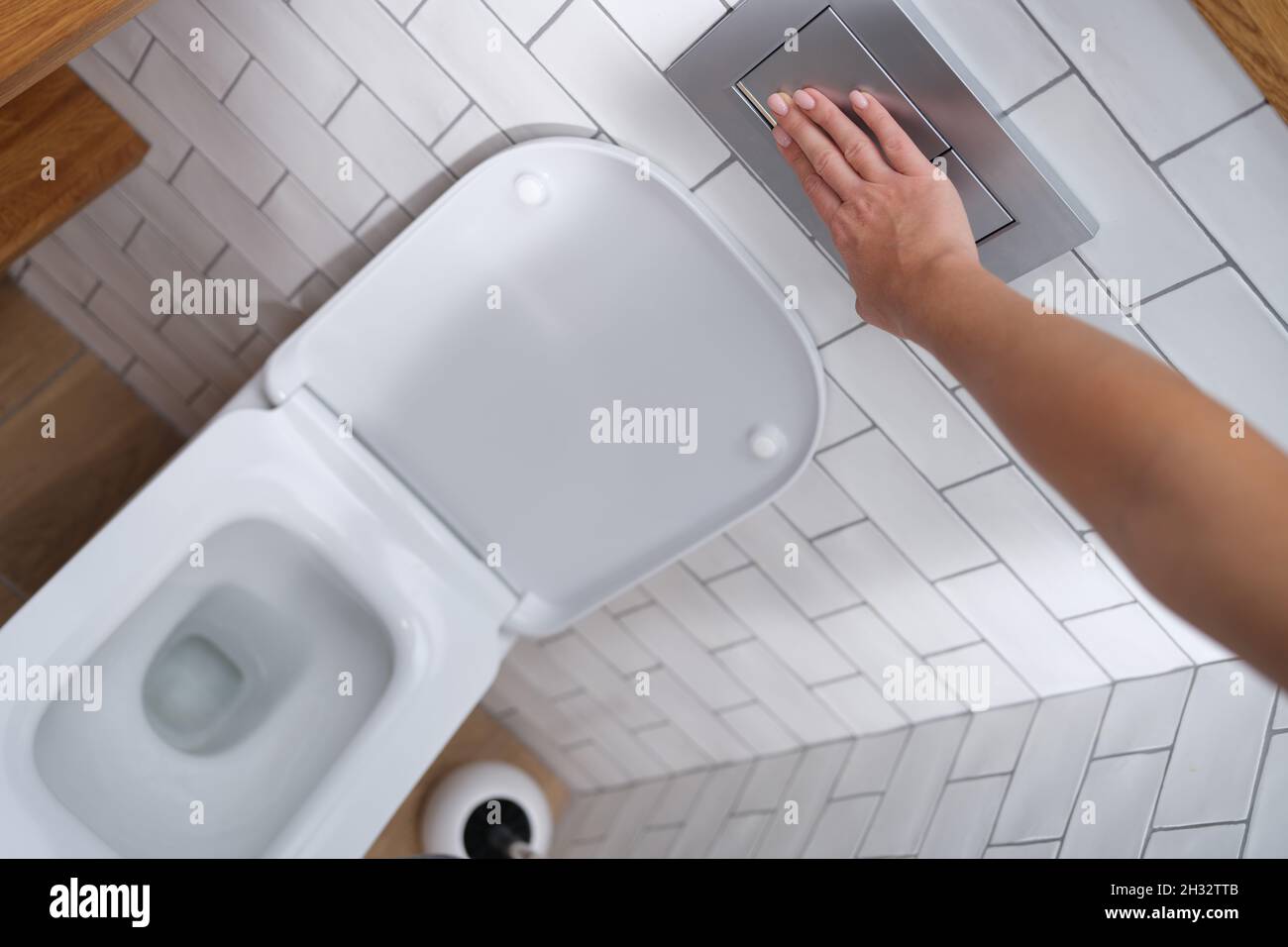 A hand presses the toilet bowl flush, close-up Stock Photo - Alamy