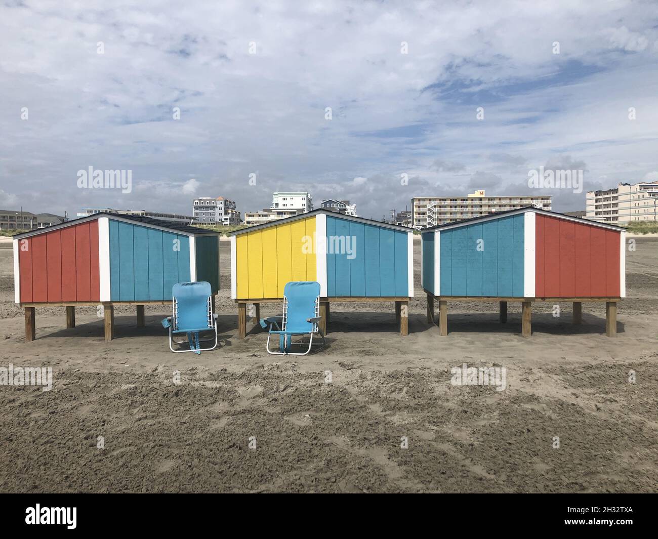 Row of colorful wooden changing rooms and chairs on the beach Stock ...