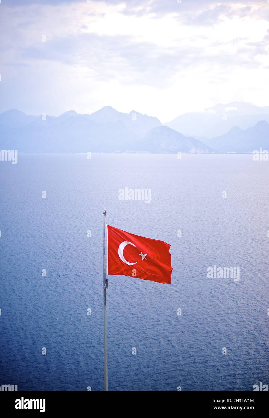 Vertical shot of Turkish flag in front of Mediterranean mountains and ...