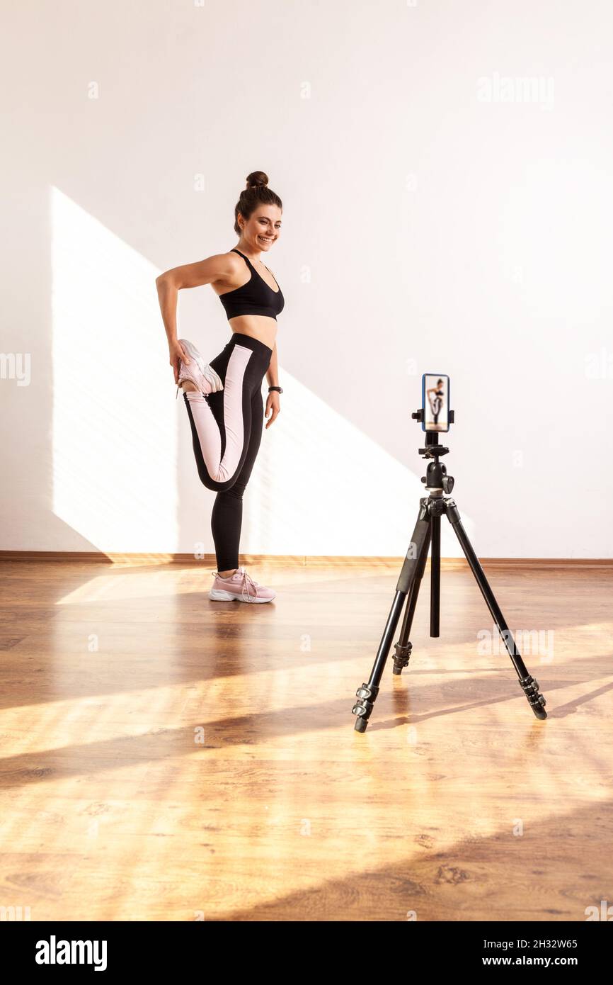 Athletic coach standing on one leg, stretching muscles before training ...