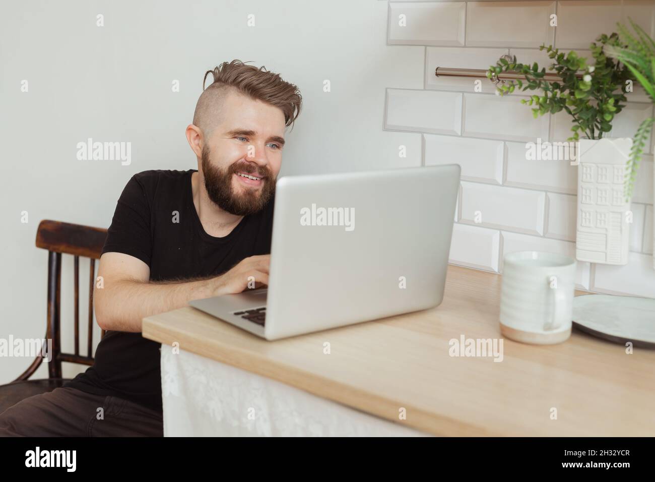 Happy smiling young man watching and working on computer laptop at home ...
