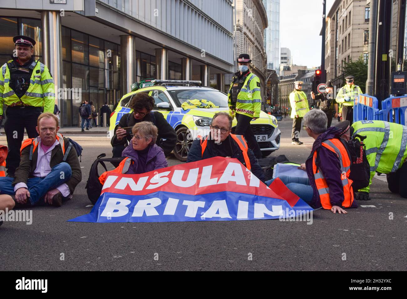 London, UK. 25th Oct, 2021. Protesters sit on the road with an Insulate ...