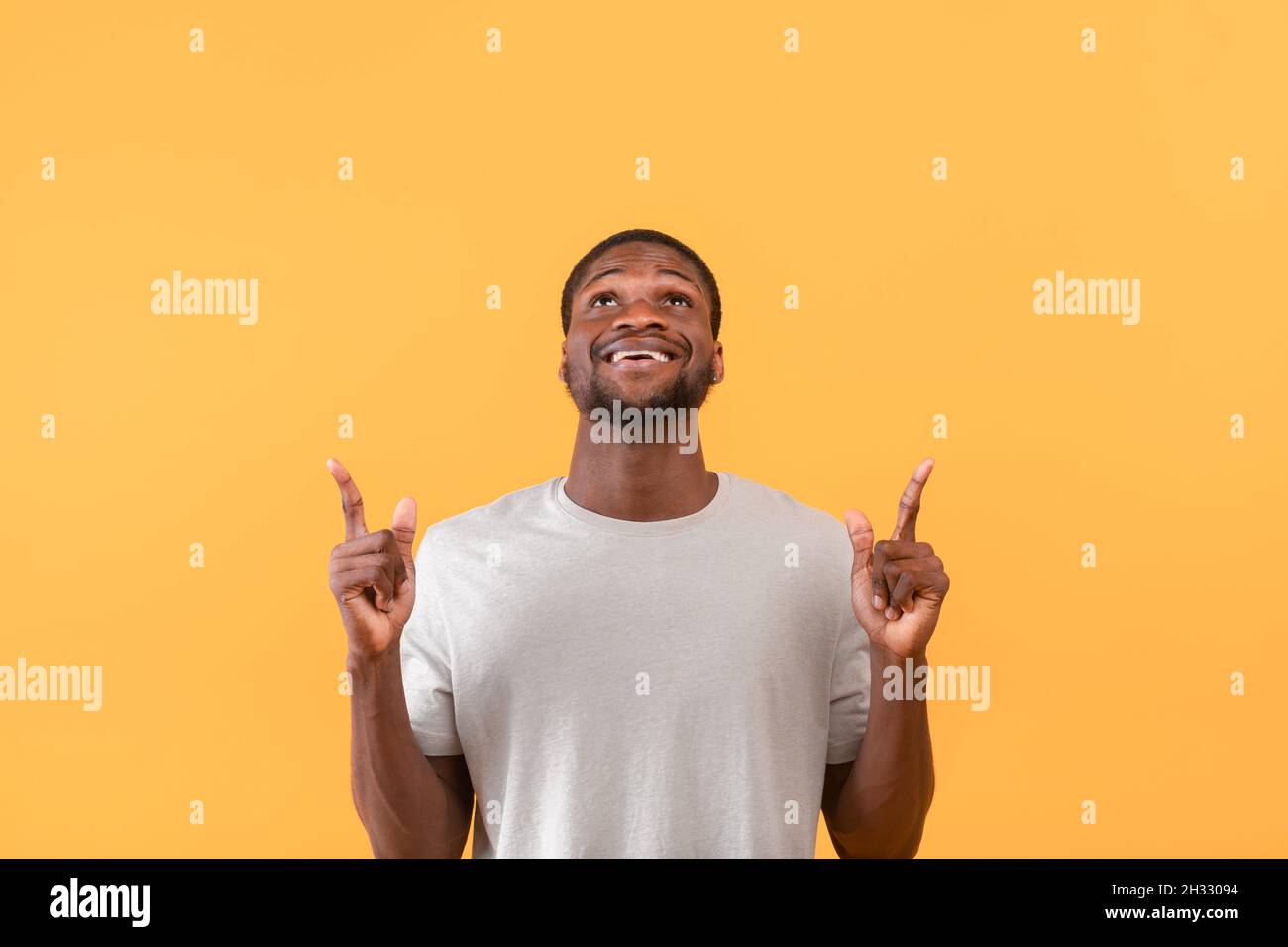 Look here. Positive black man pointing up at free space above his head ...