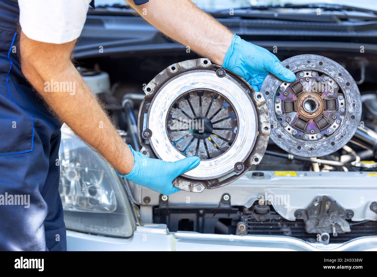 Auto mechanic holding used car pressure plate and clutch disc in front ...