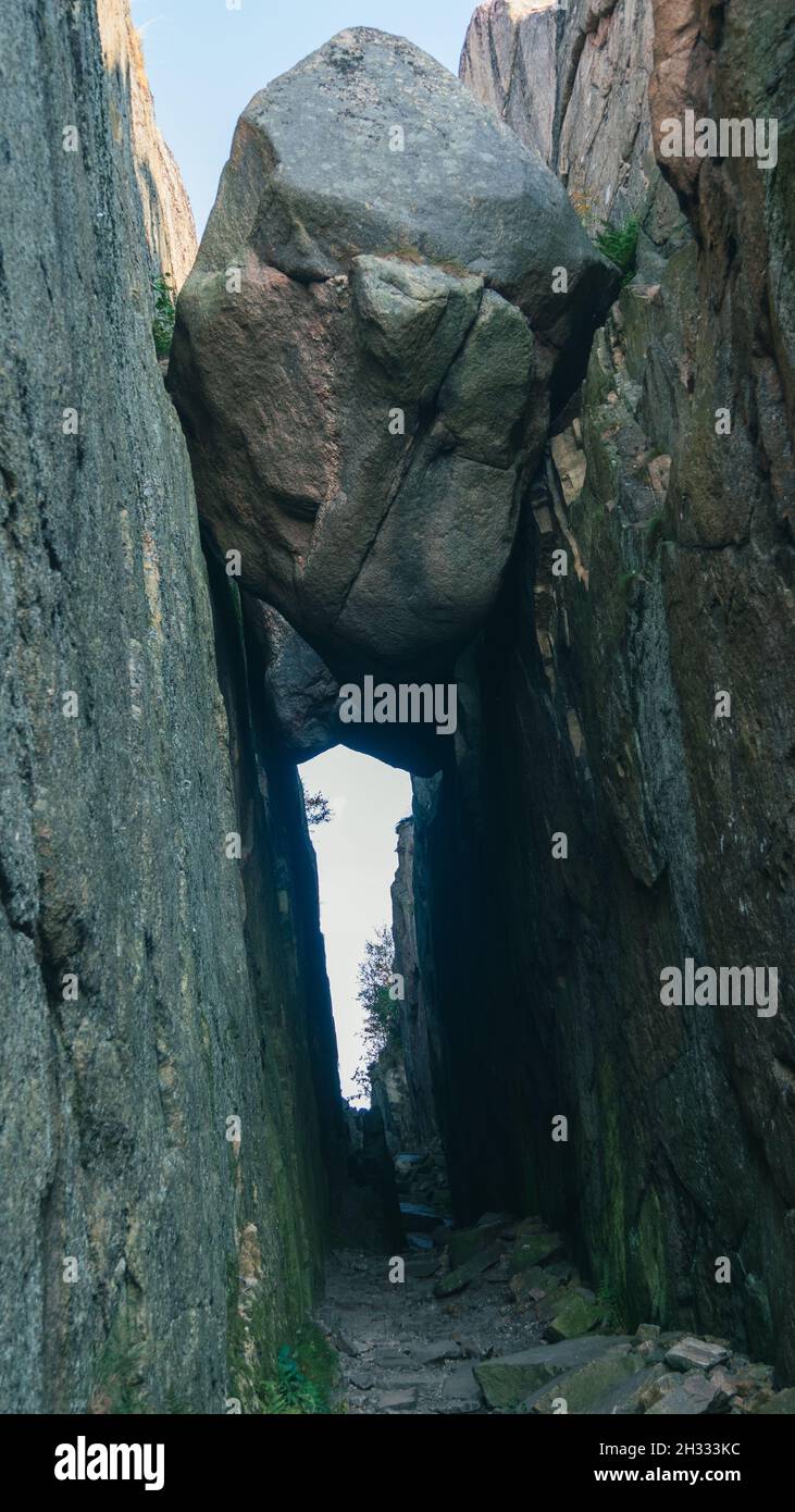 Low angle vertical closeup view of a big rock stuck in between two ...