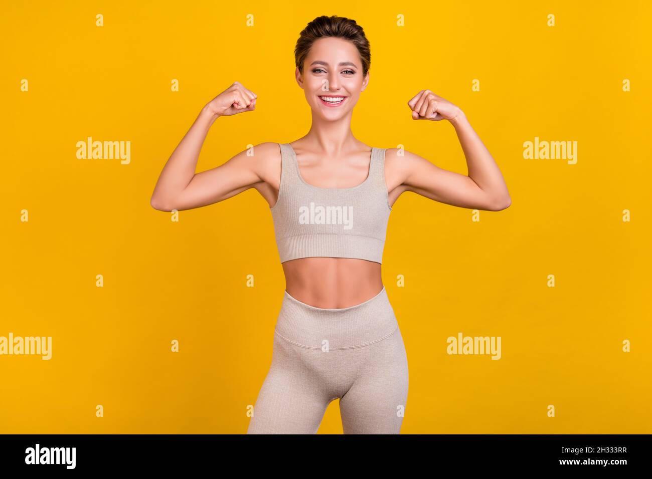 Portrait of attractive slender sportive cheerful girl demonstrating ...
