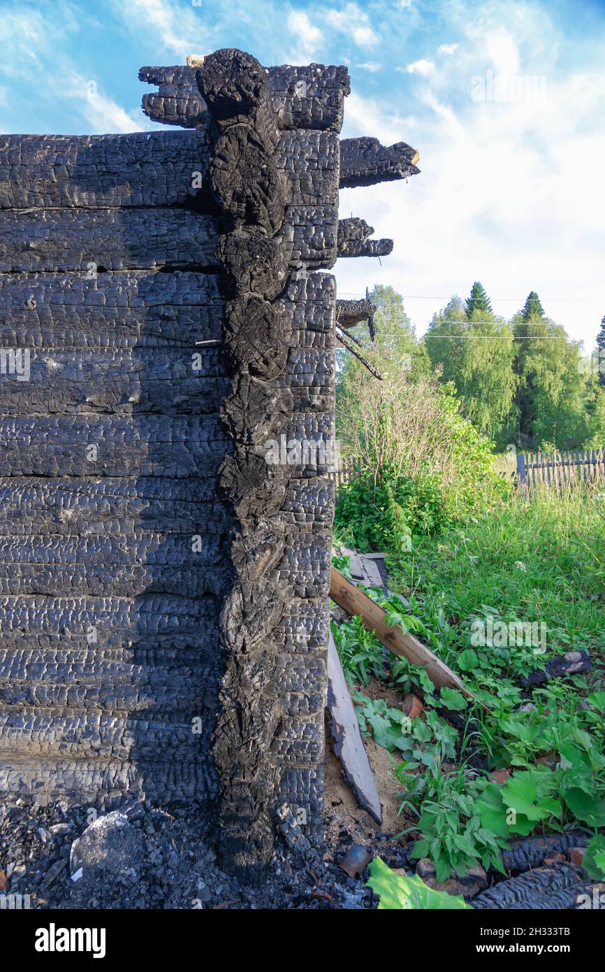 Burnt old log house in the village on a bright summer day against the ...