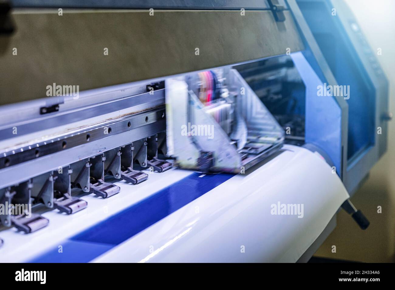 Large inkjet printer printing blue color on vinyl paper in workshop ...