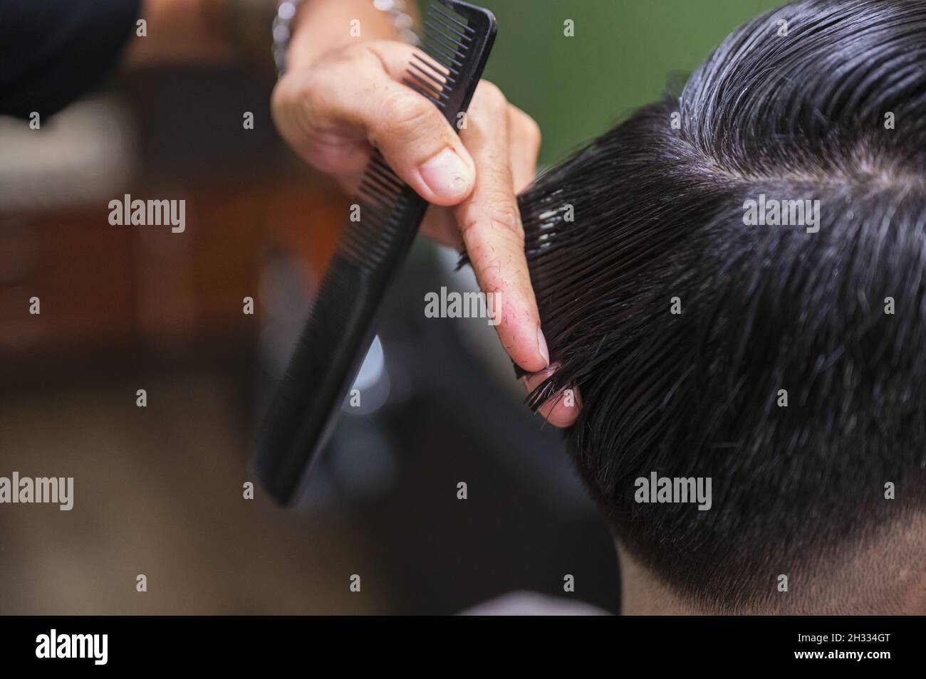 Barber cutting haircut the client hair with scissors and comb in ...