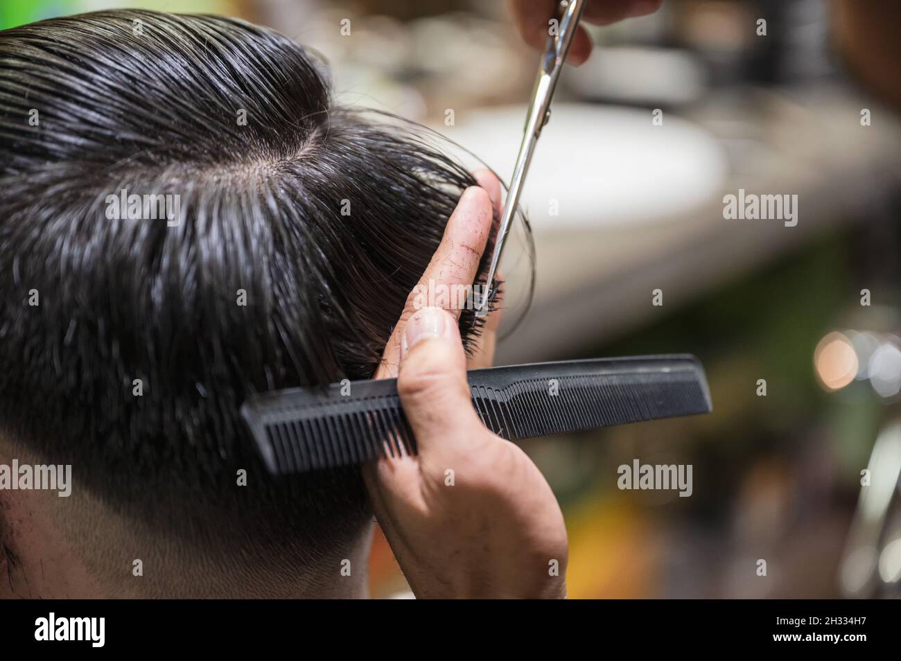 Barber cutting haircut the client hair with scissors and comb in ...