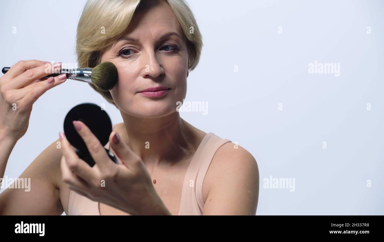 blonde middle aged woman applying face powder isolated on white Stock ...
