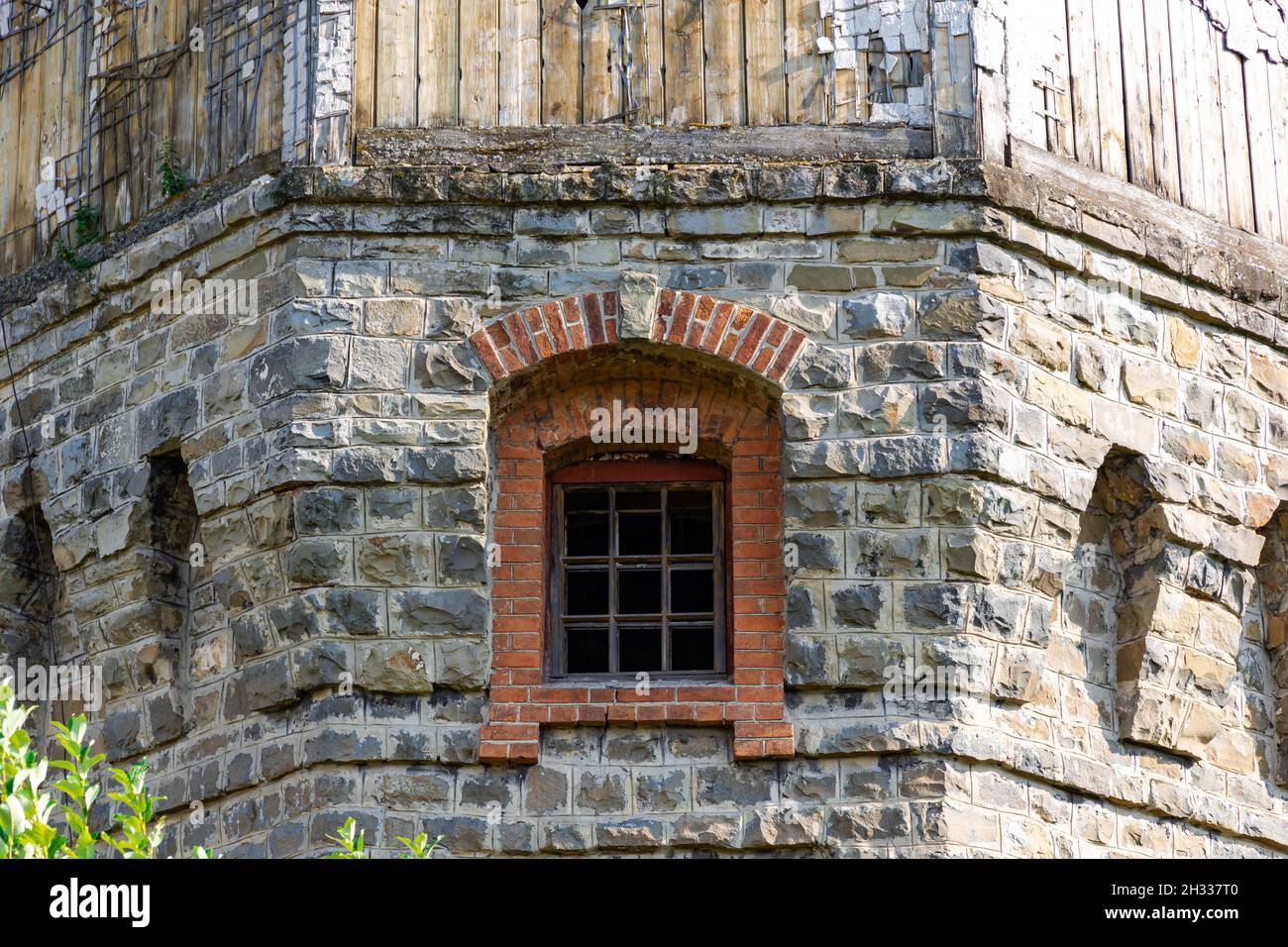 Red brick window of an ancient castle in a wall of natural gray stone ...