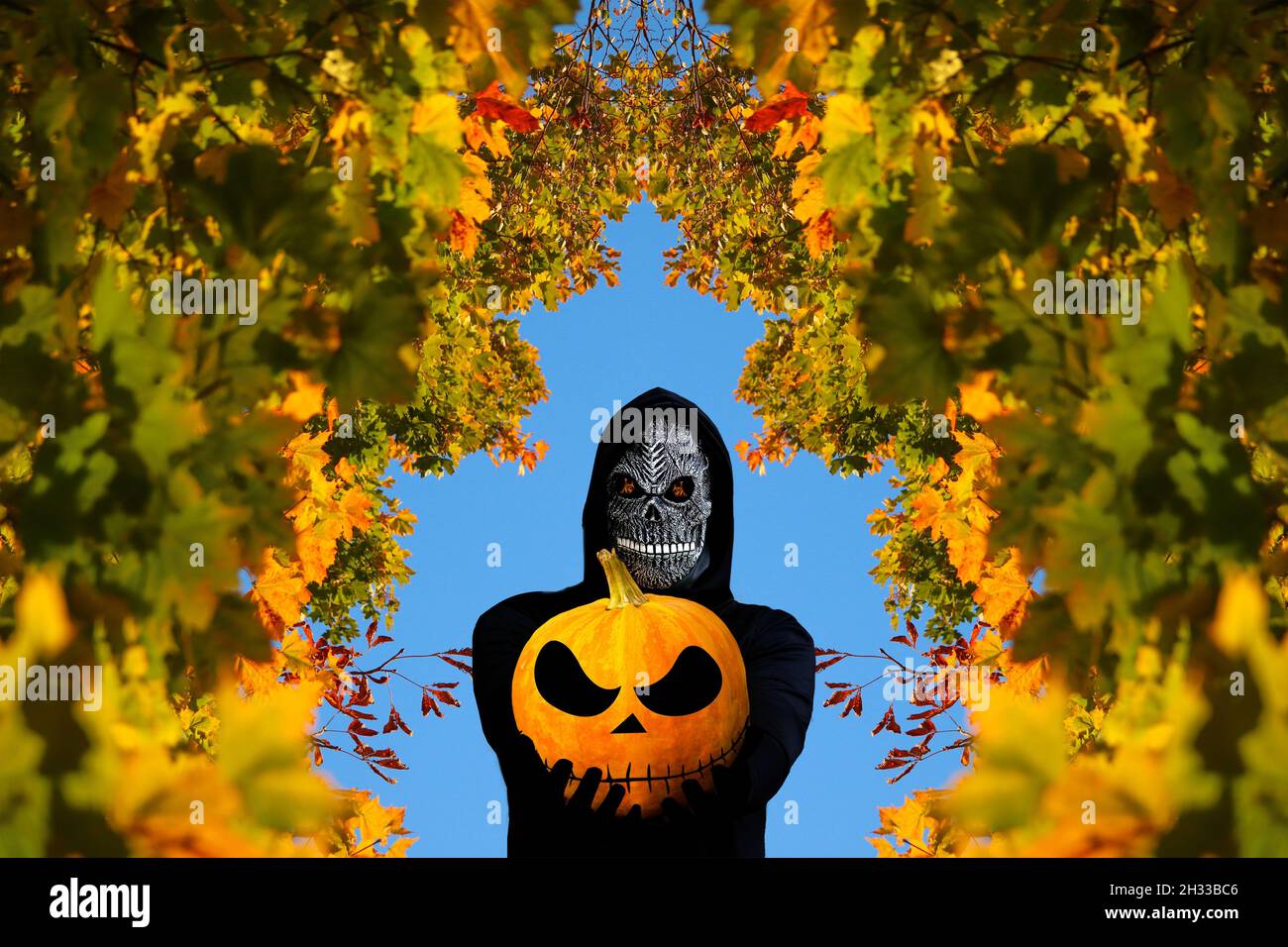 Grim reaper holding halloween pumpkin head. Man in death mask with fire ...