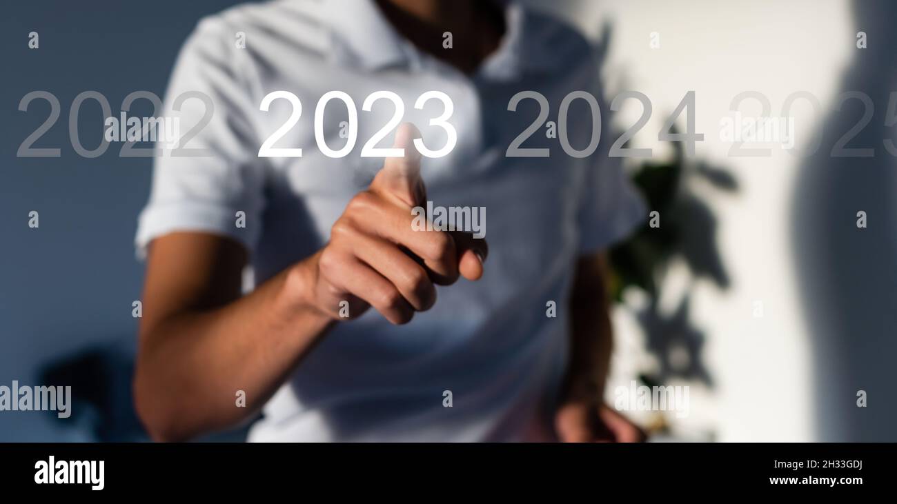 Finger pressing blue start 2023 button on virtual interface on gray ...