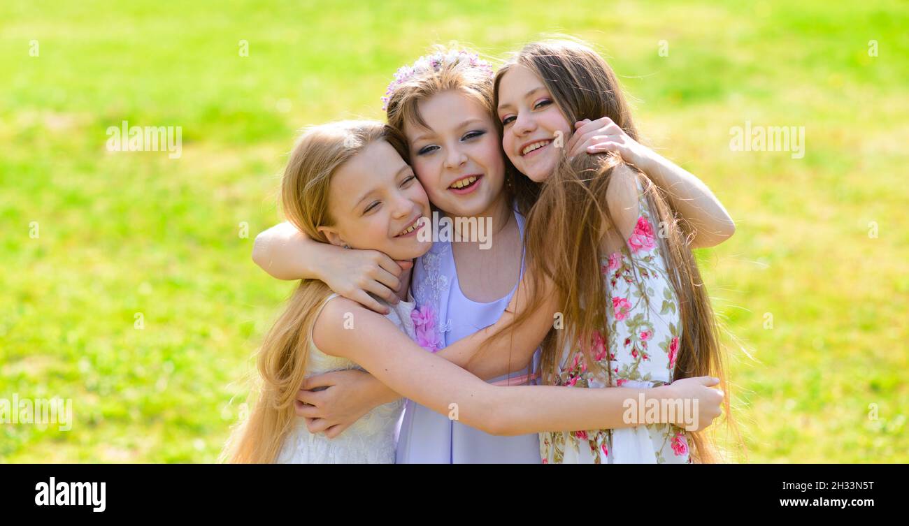 Three adorable girls in dresses hold hands in a circle holding hands ...