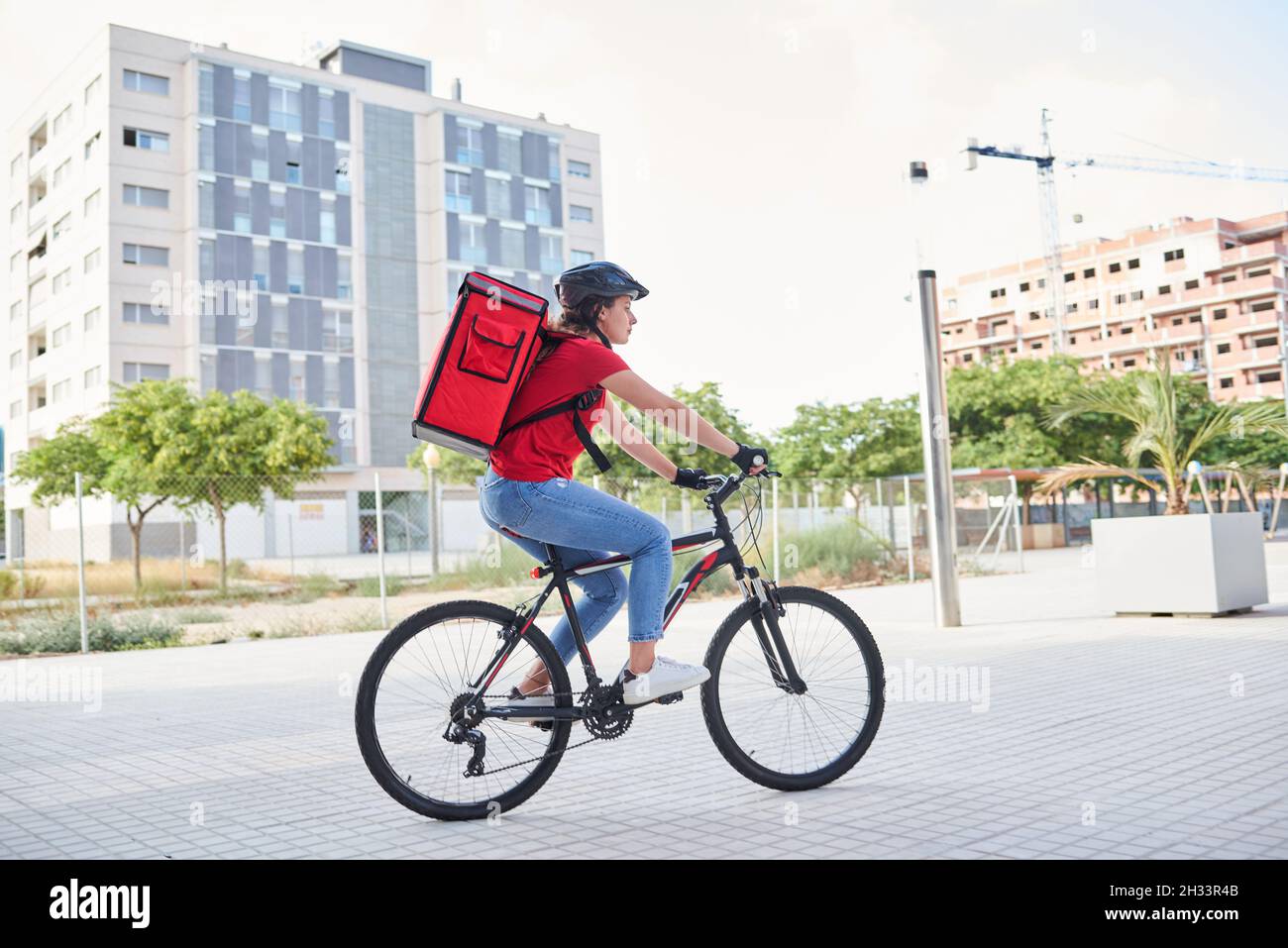 Food delivery woman riding bicycle in city Stock Photo - Alamy