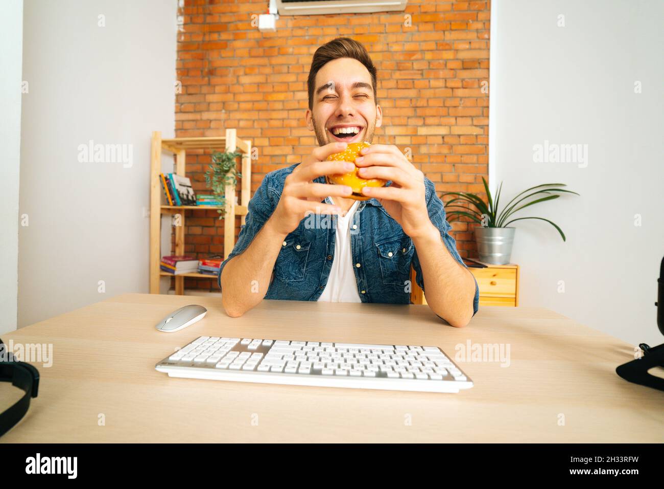 Front view of laughing hungry young man holding hamburger with beef ...