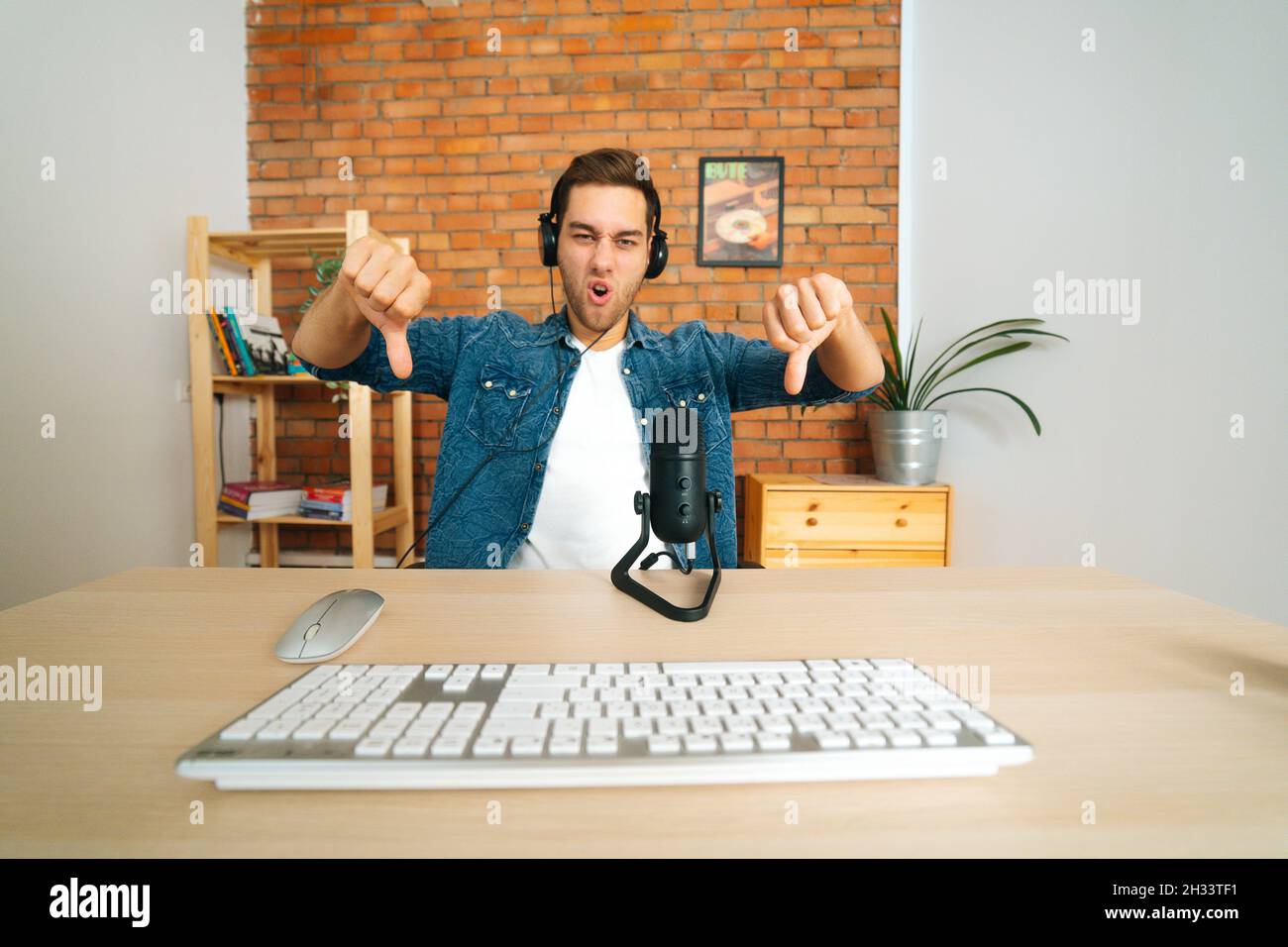 Front view of negative angry male blogger streaming live podcast using ...