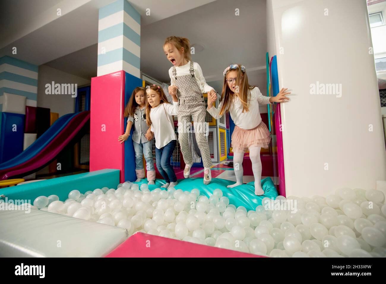 Group of happy little girls jumping into ball pit Stock Photo - Alamy