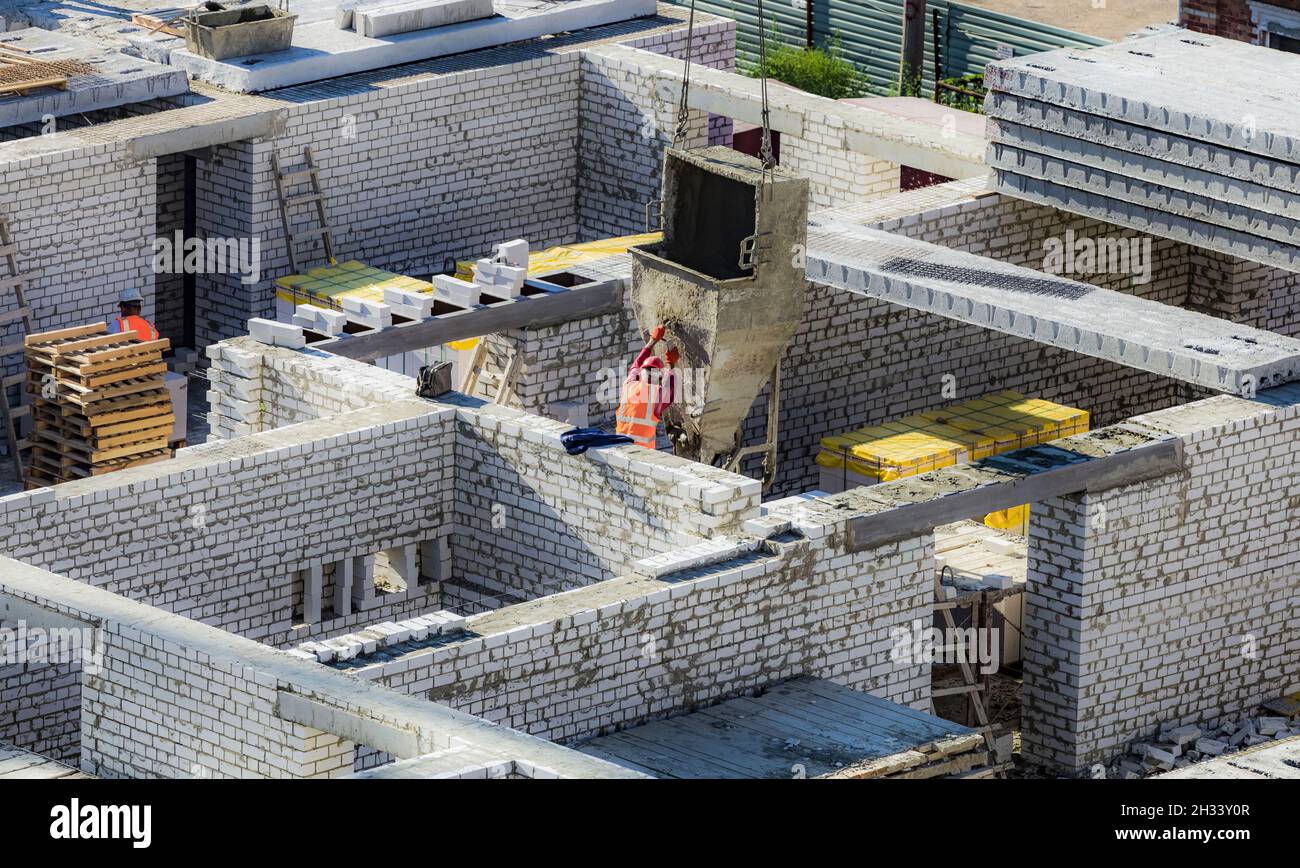 Bricklayer worker in safety orange vest and hard hat make walls of ...