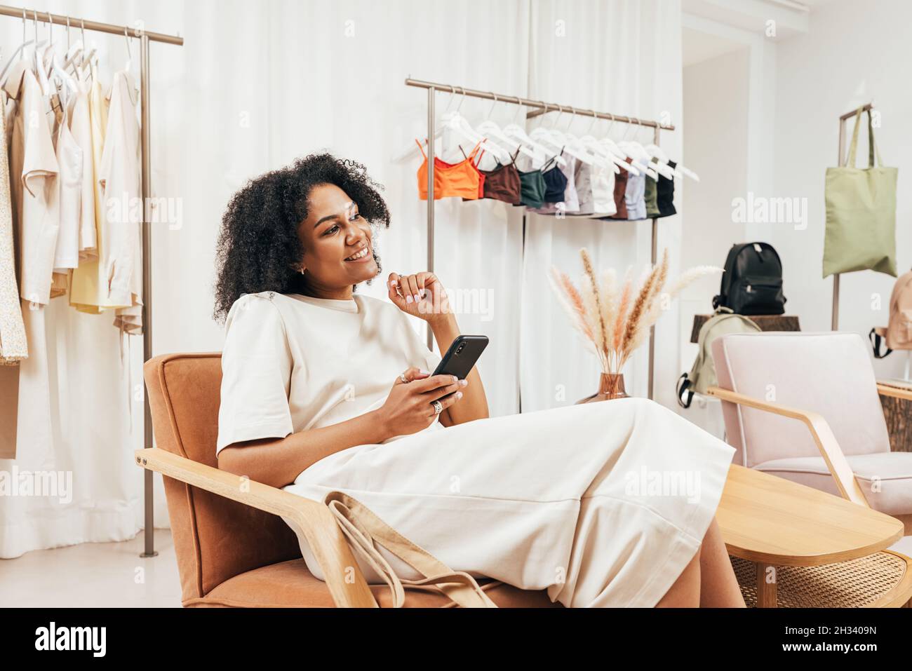 Side view of a stylish customer holding mobile phone while relaxing on ...