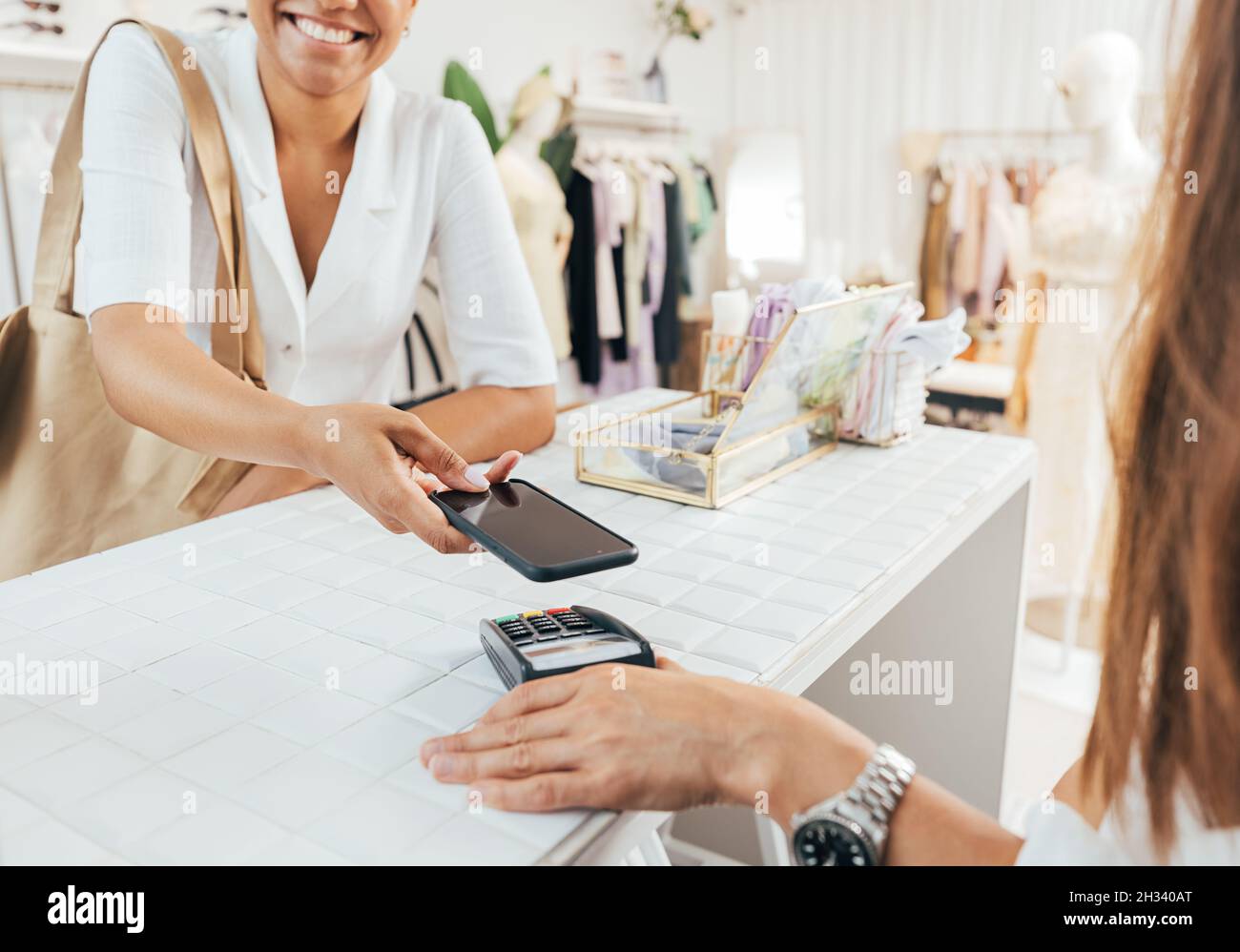 Cropped shot of a smiling young woman using smart phone to pay at ...