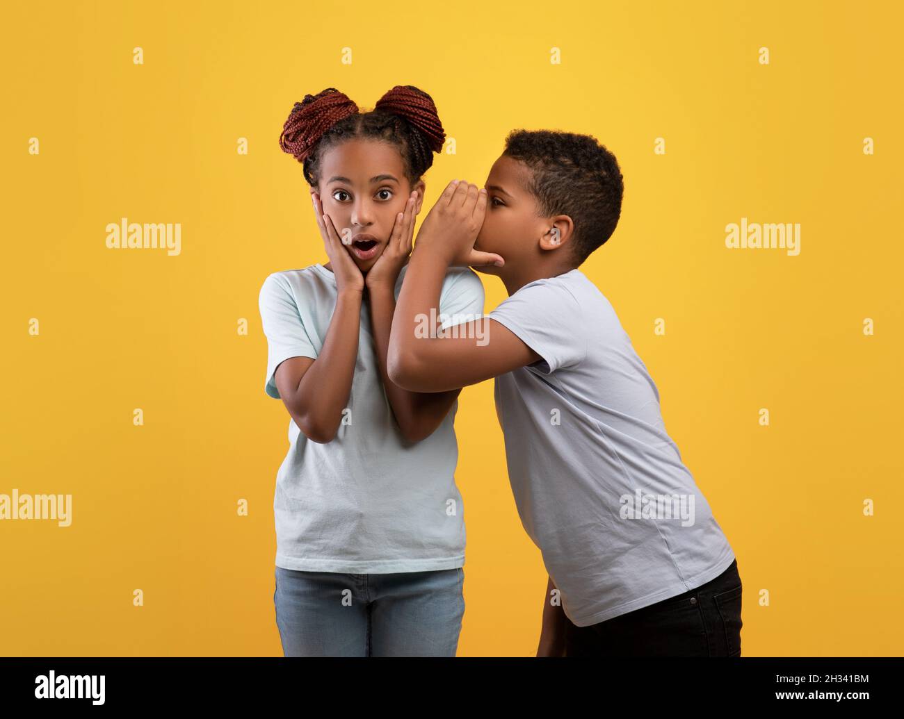 Black boy brother sharing secrets with his shocked sister, african ...