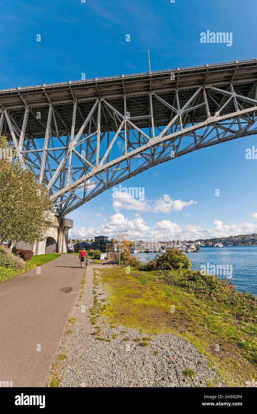 A cyclist walks his bike on the Burke Gilman Trail near the underside of the Aurora Bridge near ...