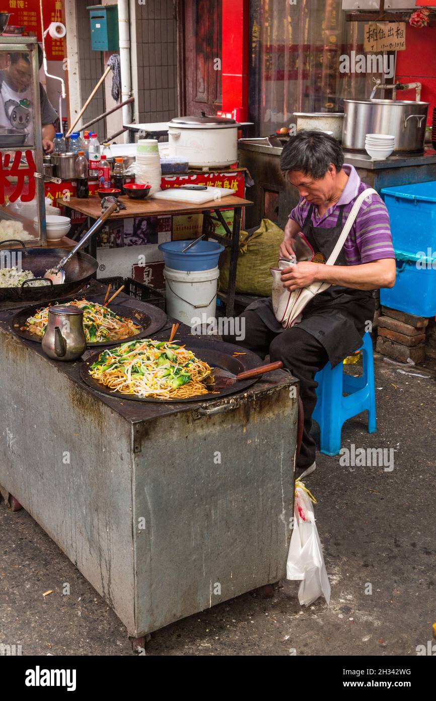 A vendor selling stir fried noodles on the street in the Old Town ...