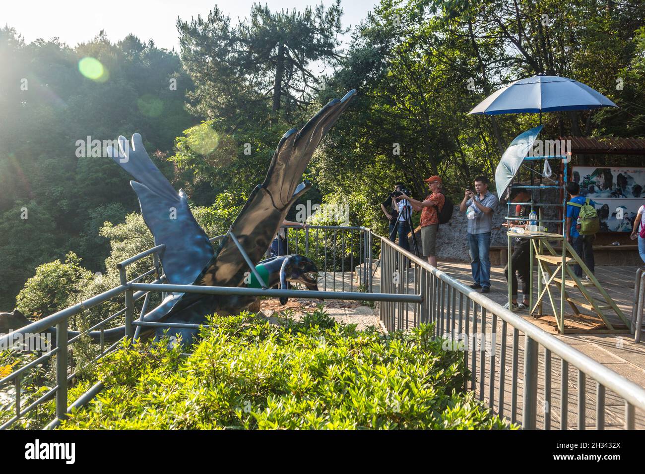 Tourists photograph the statue of a dragon-like mountain banshee from ...