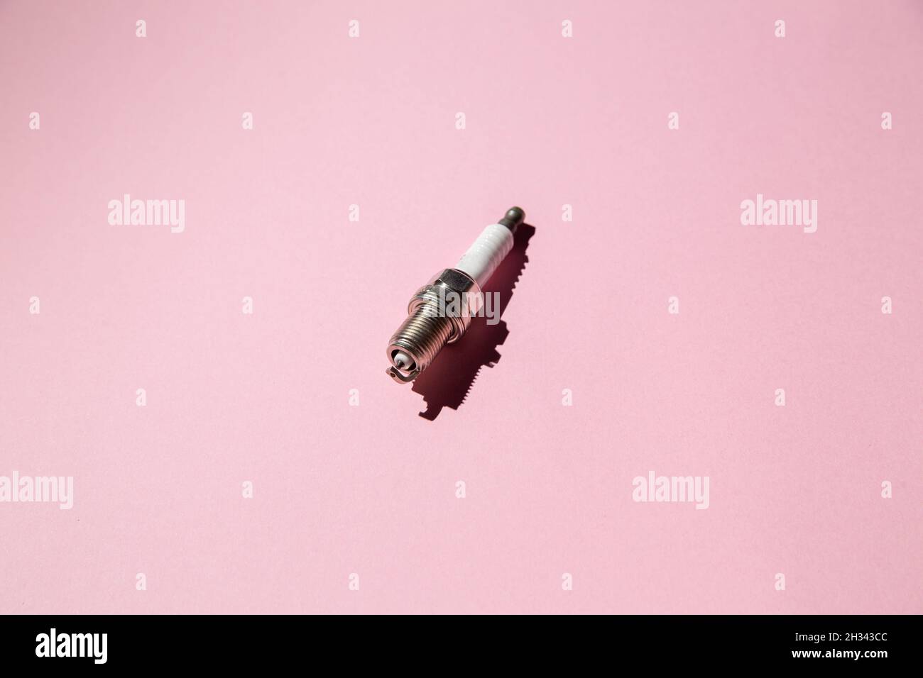 Spark plug. Car candle lies against a pink background. Auto engine ...