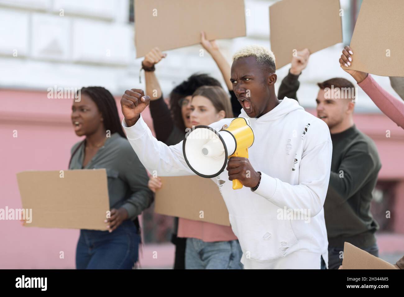 Angry black guy activist with megaphone on the street, chanting slogans ...