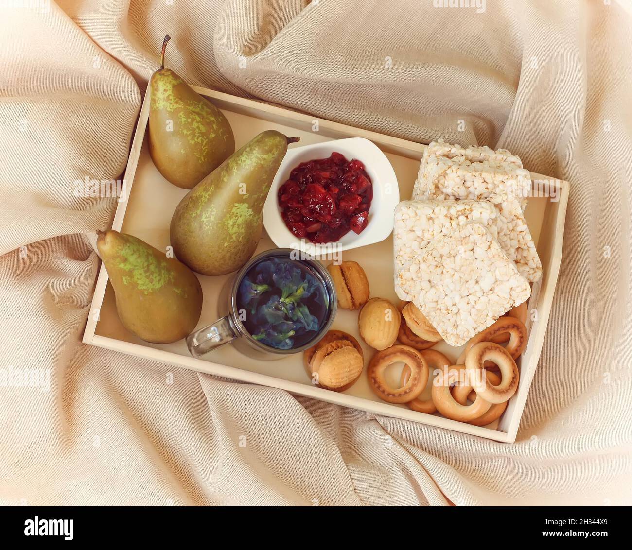 Breakfast in bed in a wooden tray with pears, pear jam, bisquits, sweet ...