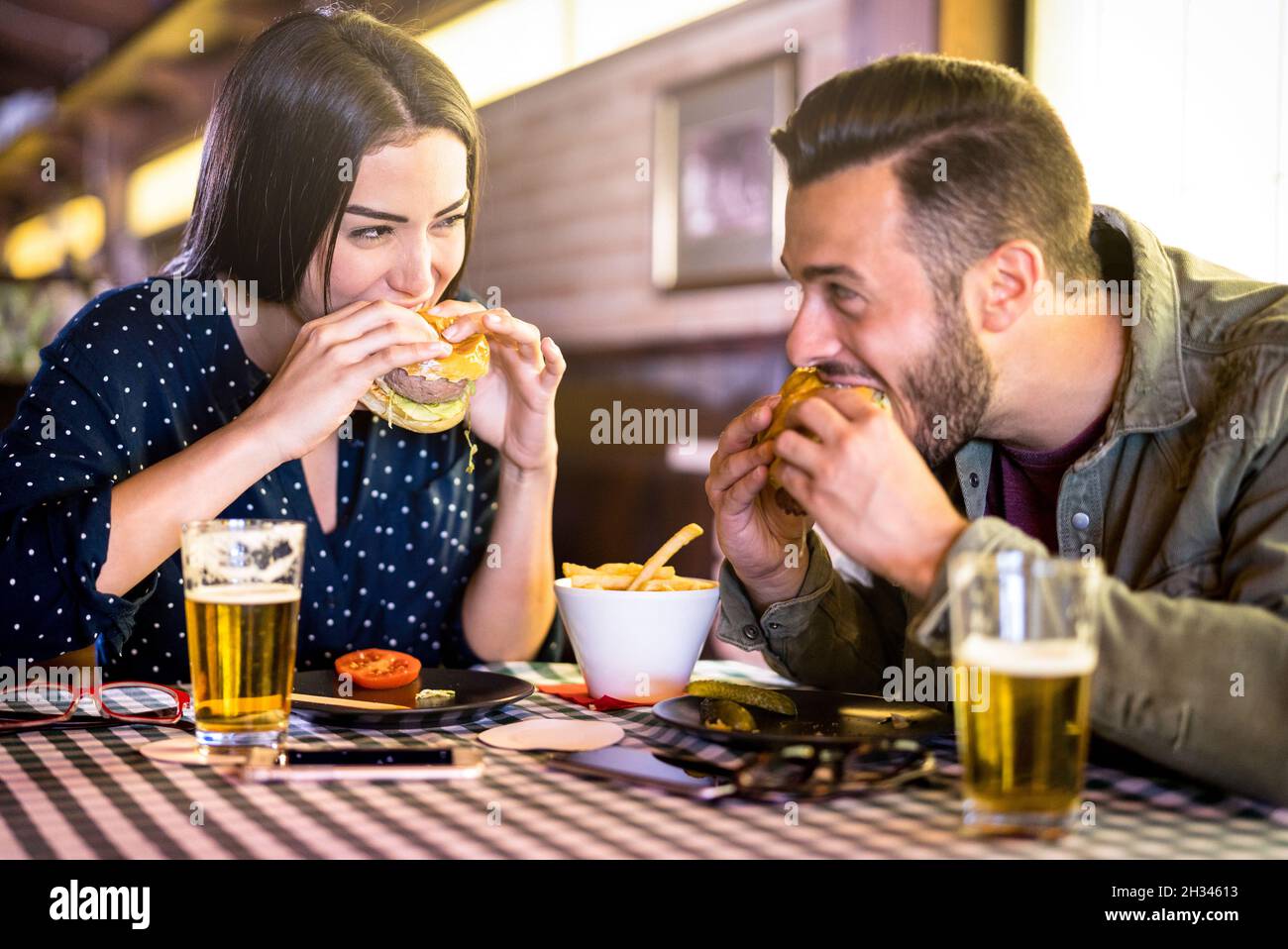 Happy couple having fun eating burger at restaurant pub fast food ... Happy couple having fun eating burger at restaurant pub fast food ...
