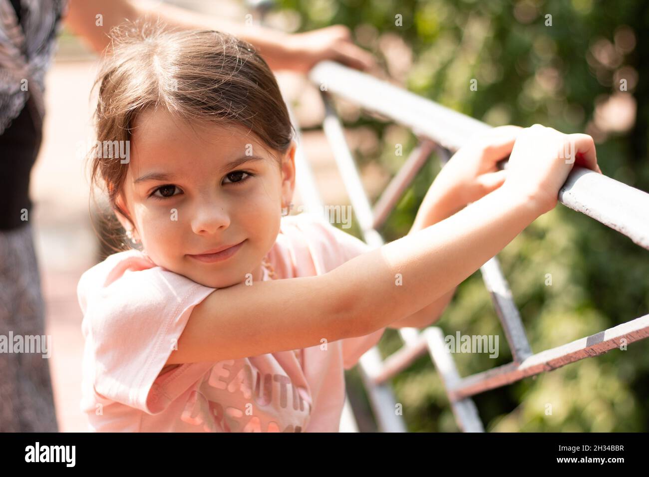 Little beautiful girl with a ponytail leans on the handrail Stock Photo ...