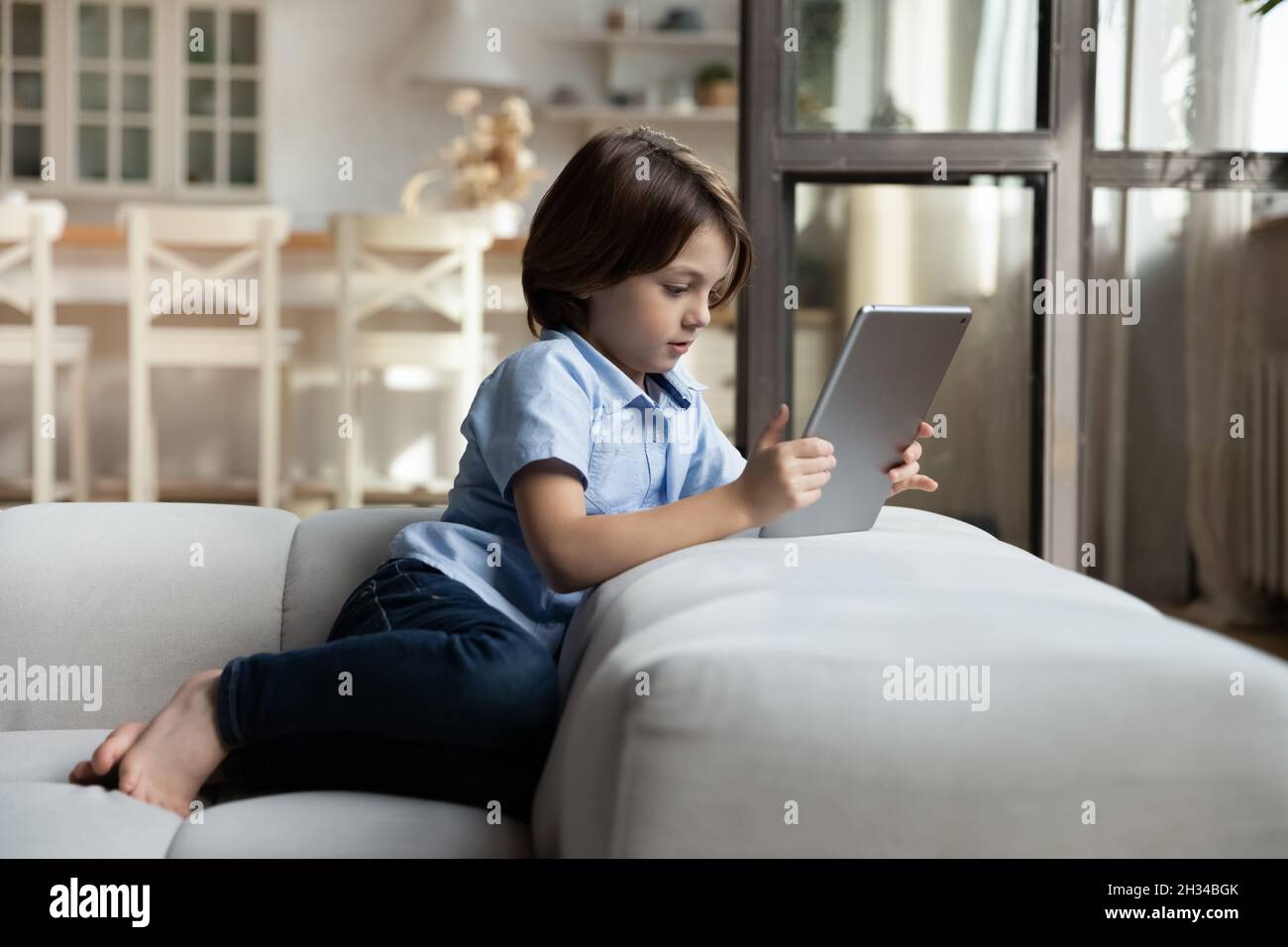 Smart focused primary school boy reading book on tablet computer Stock ...