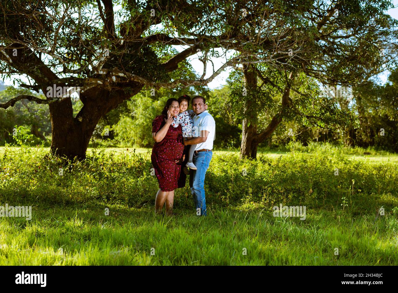 sian mother, father and toddler daughter spending time outdoors reading ...