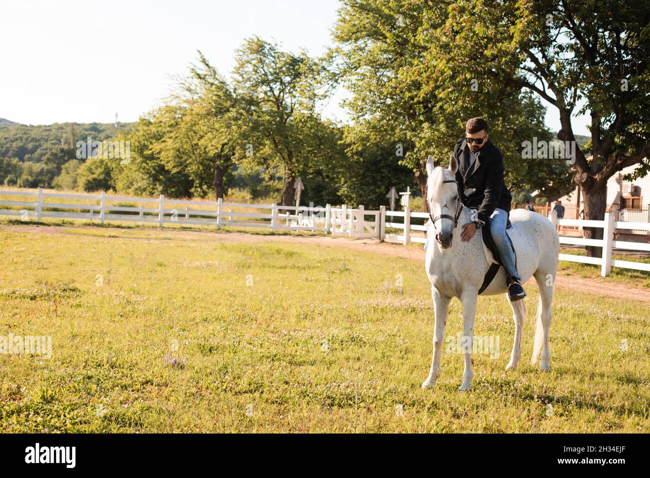 The handsome man rides a horse on a ranch Stock Photo - Alamy