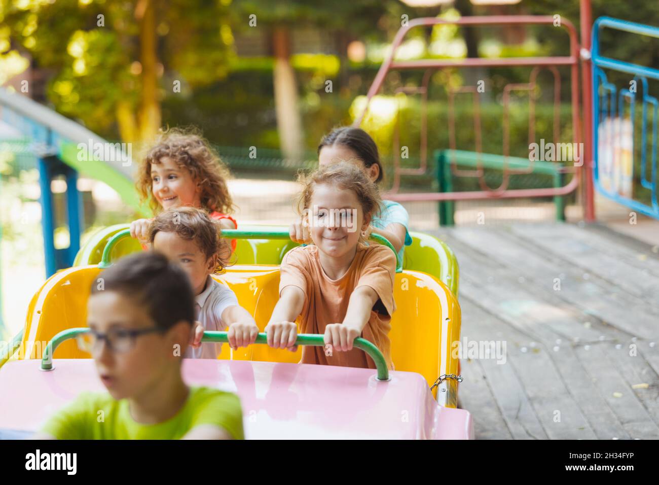 The happy kids on a roller coaster in the amusement park Stock Photo ...