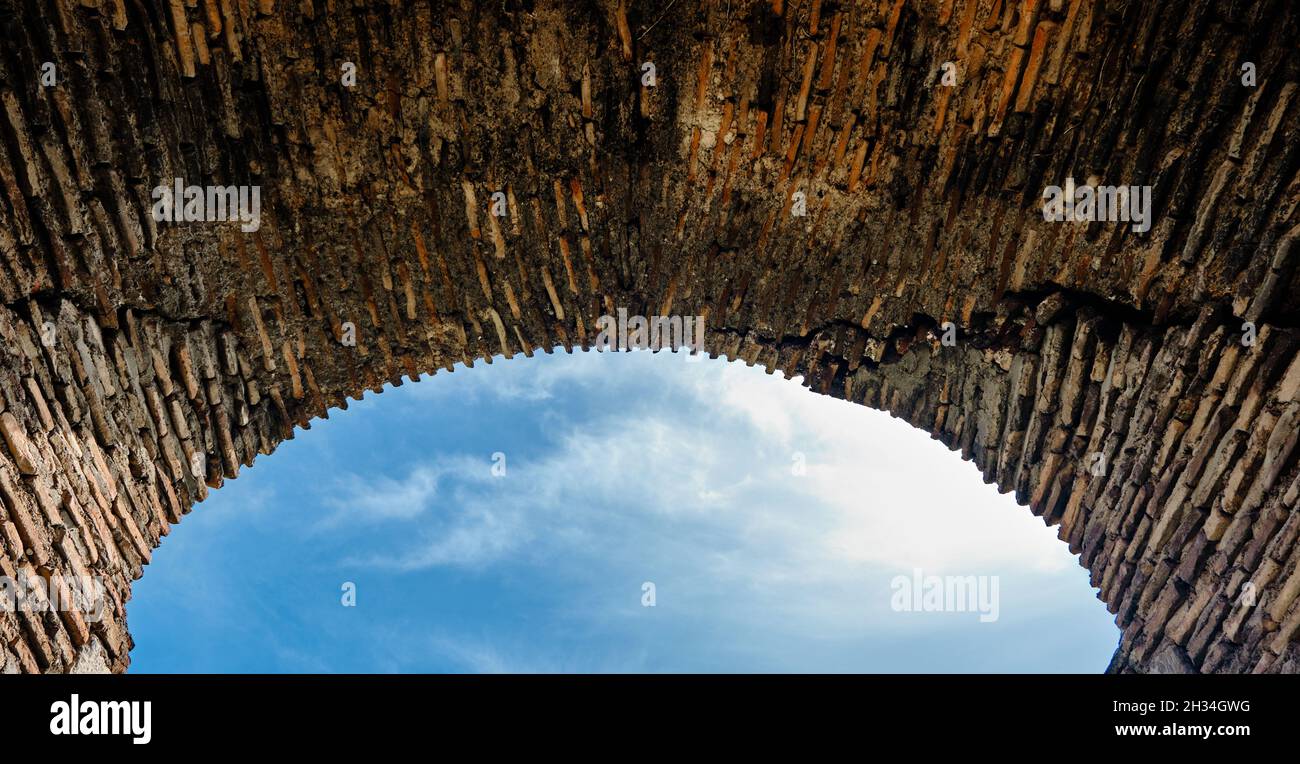 architectural arch made of red bricks wall with blue sky background in ...