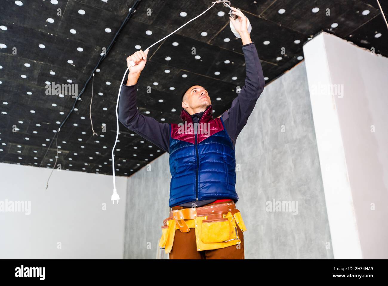 Electrician repairing ceiling light, working Stock Photo - Alamy